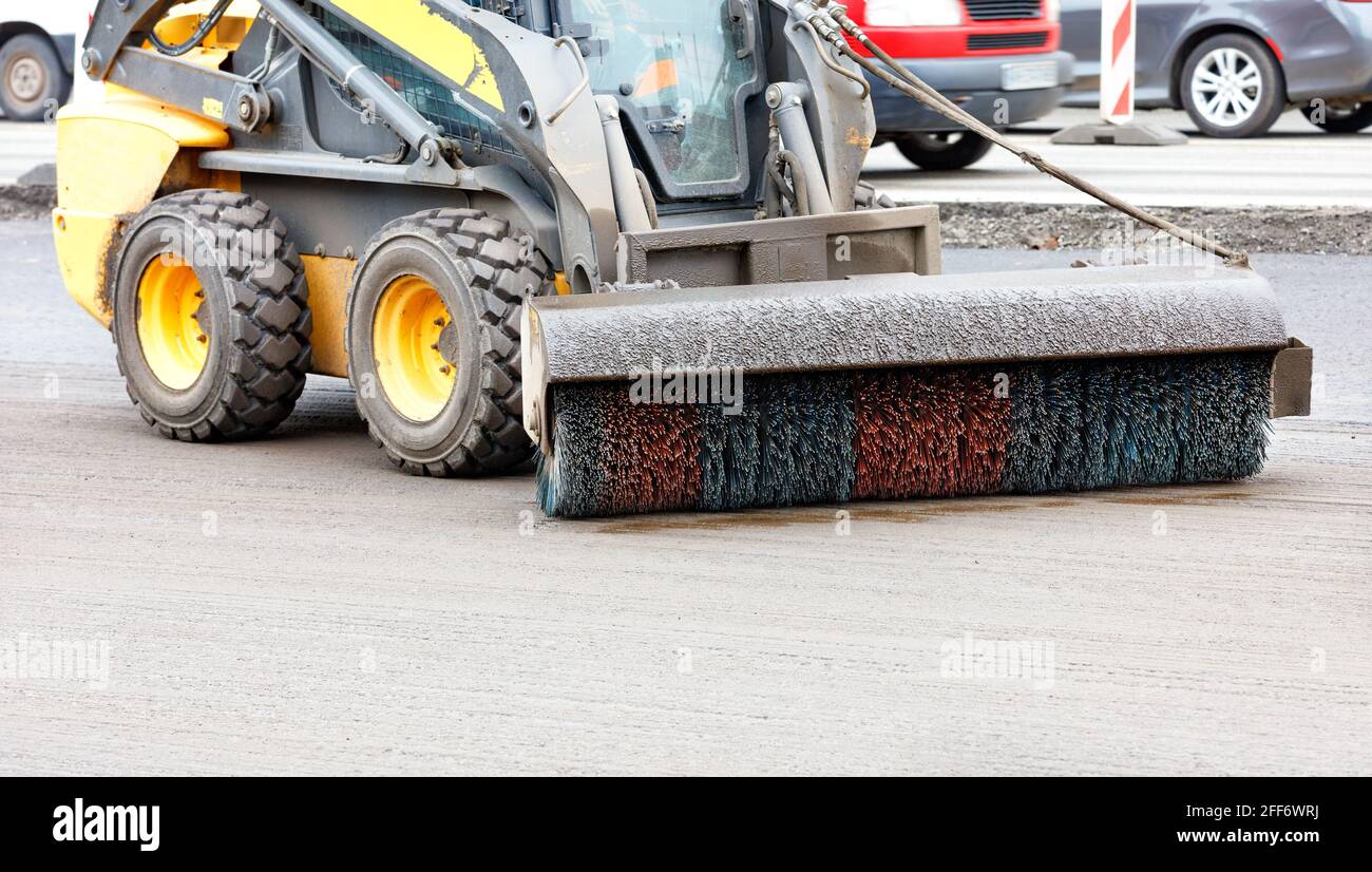 A compact grader at a construction site cleans the repaired section of ...