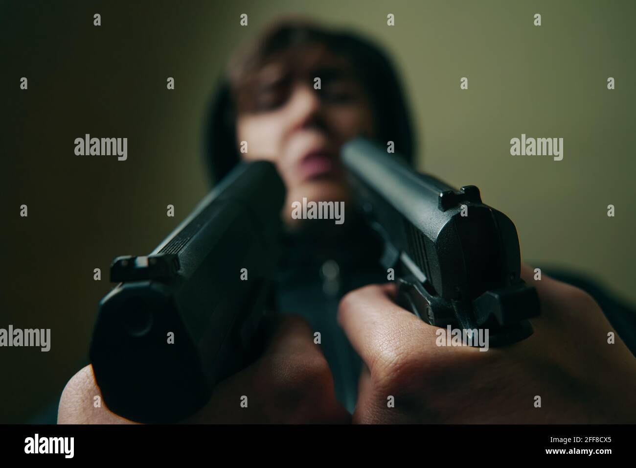 Close up of two guns pointed at man's scarred face. Threats and ...