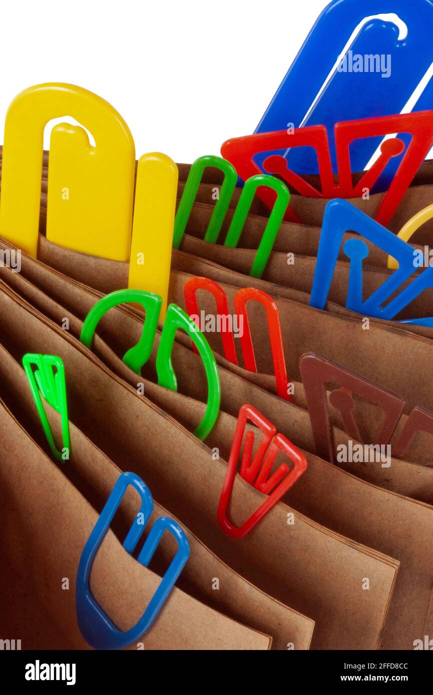 Vertical isolated closeup of 12 colorful paperclips in rows on pages of ...