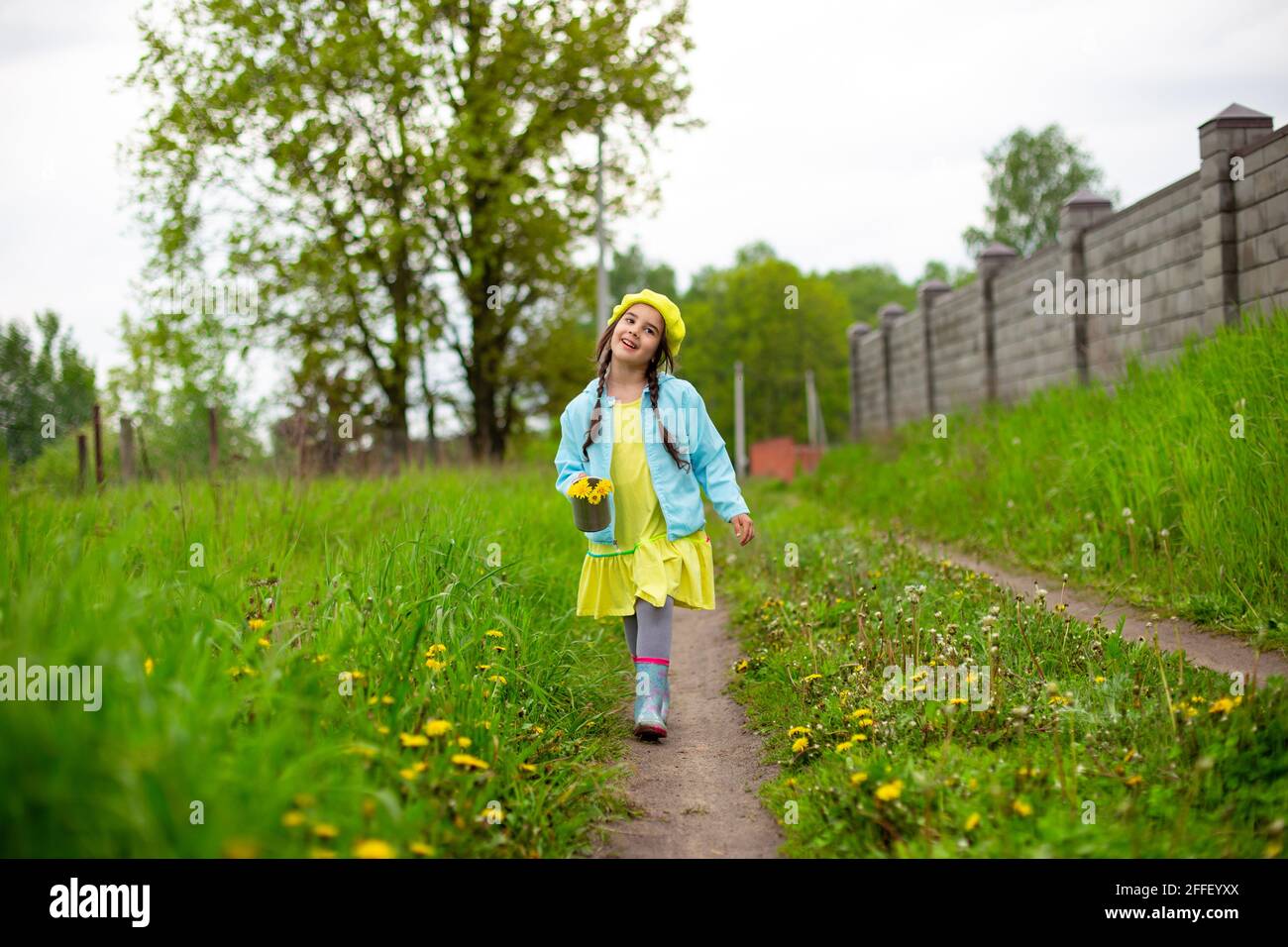 A beautiful little girl walks in the countryside along a path near a ...
