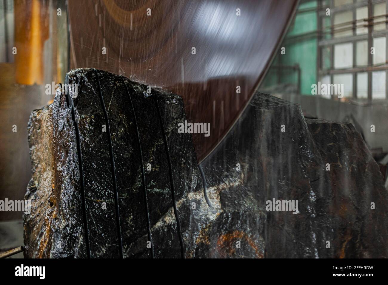 Large industrial cutting machine cuts gray granite stone into slabs ...