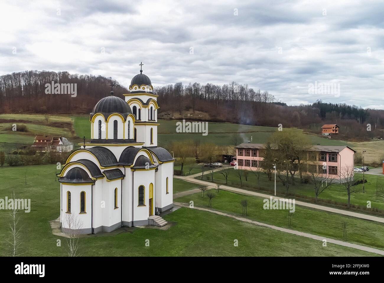 Aerial view of a church in a green field with buildings and trees in ...
