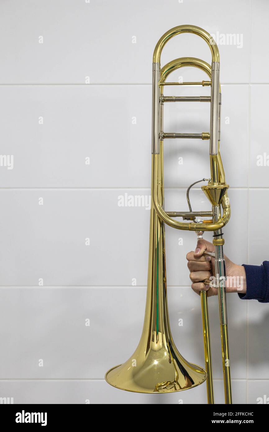 detail of a hand holding a tenor barre trombone with white background ...
