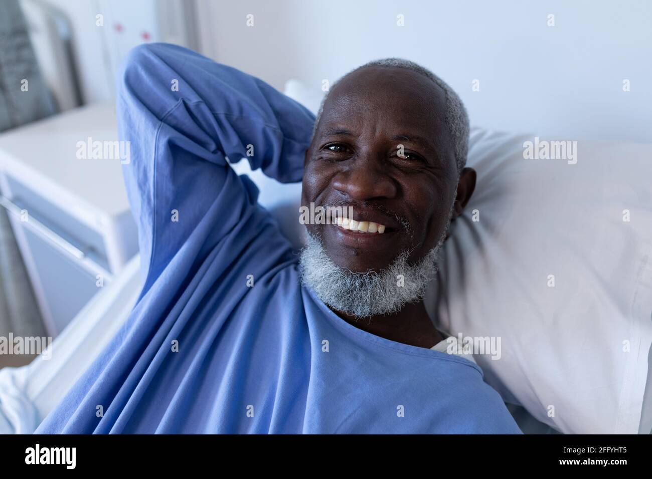 Portrait of african american male patient lying on hospital bed smiling ...