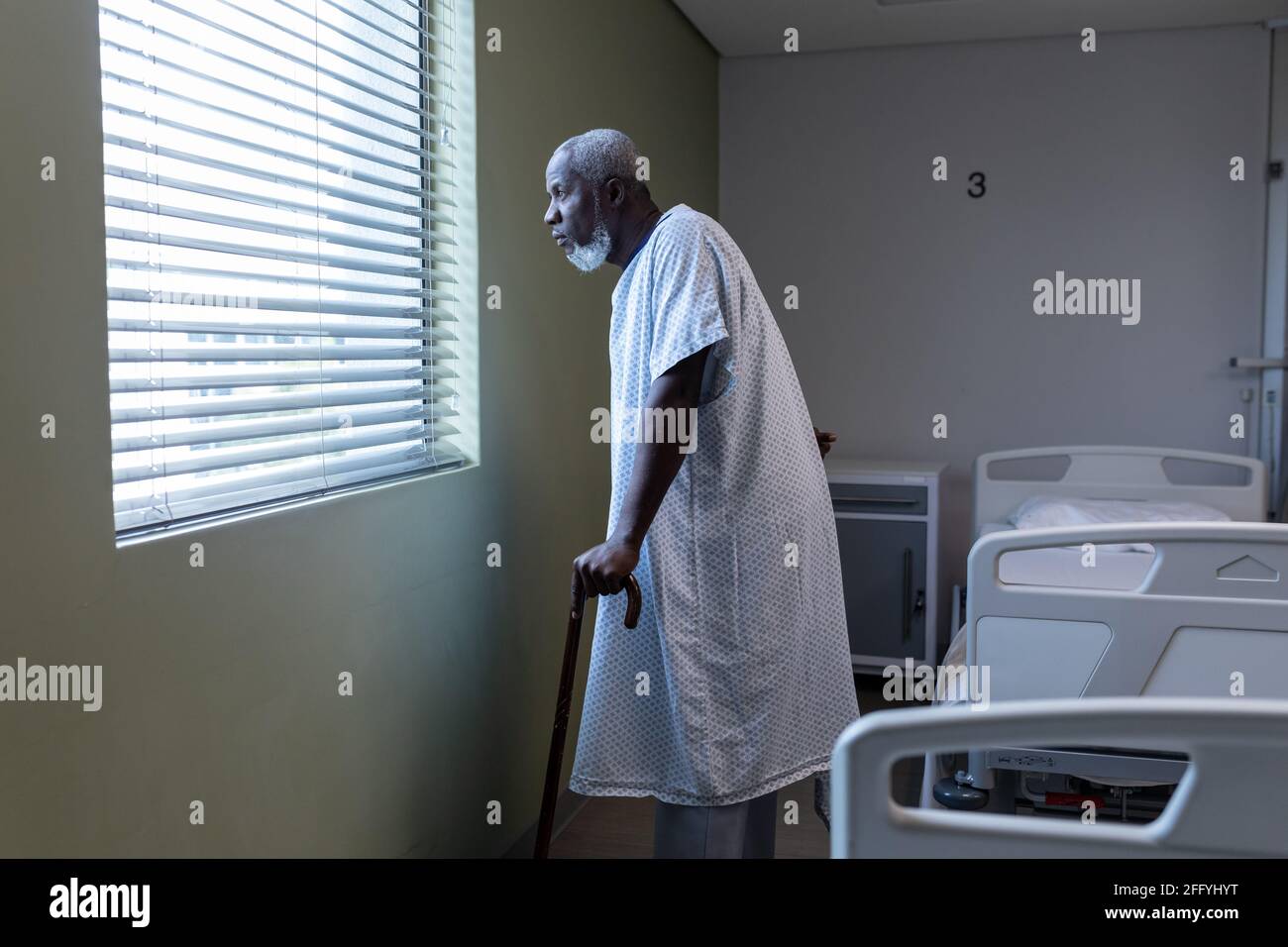 African american male patient with cane looking through the window in ...