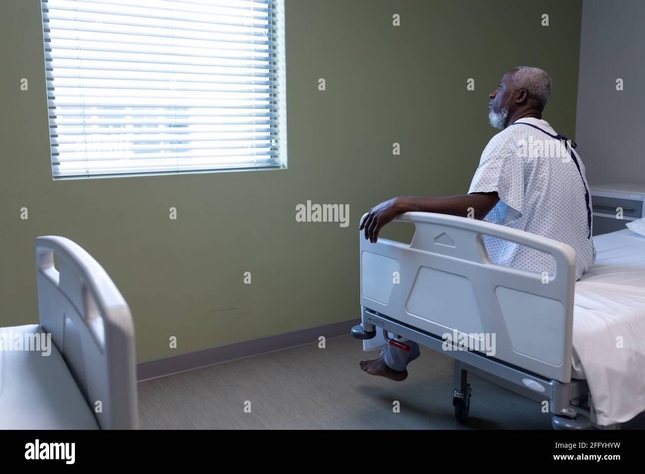 Portrait of african american male patient sitting on hospital bed ...