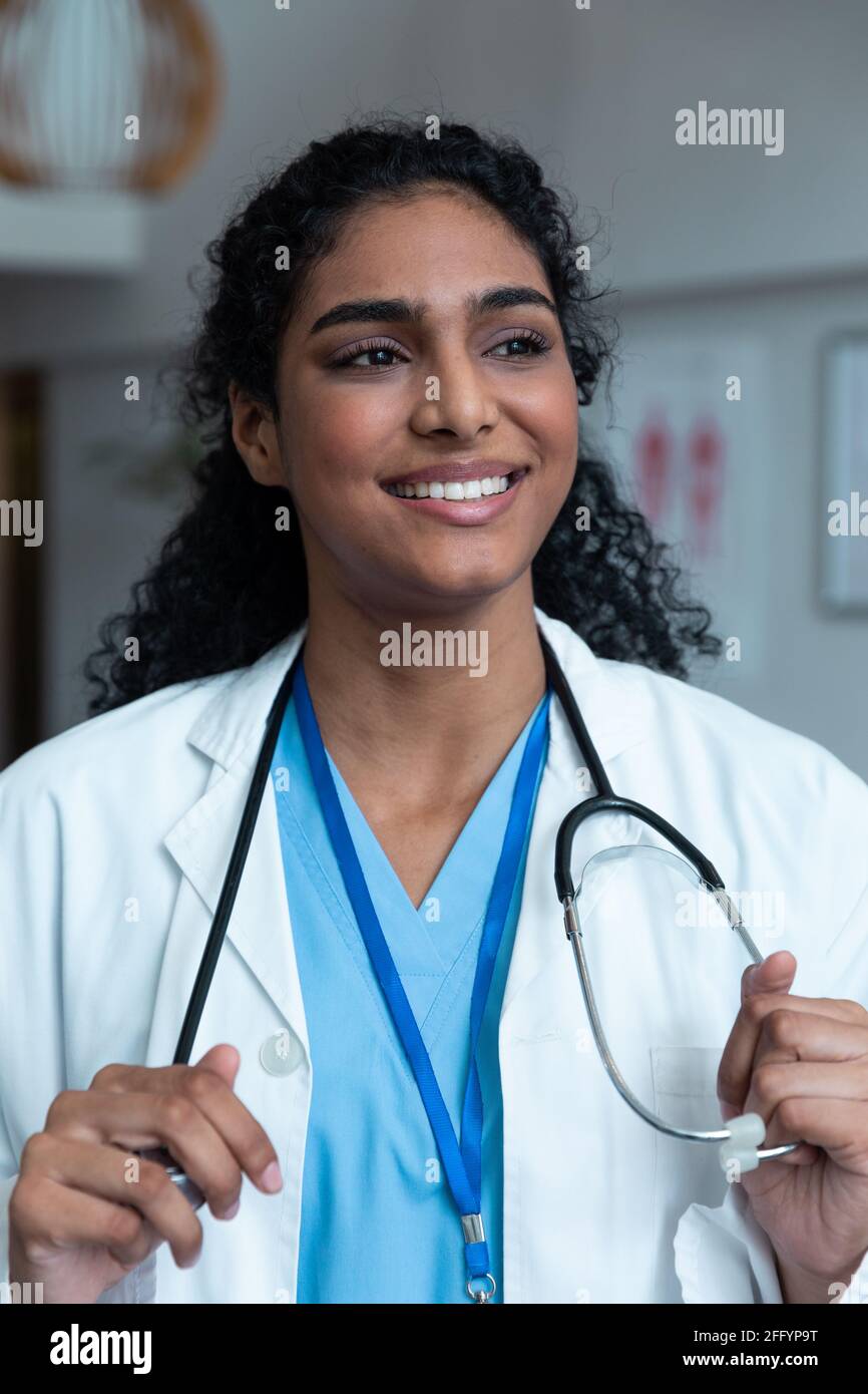 Portrait of smiling mixed race female doctor with stethoscope wearing ...