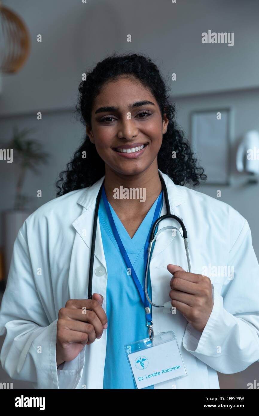 Portrait of smiling mixed race female doctor with stethoscope wearing ...