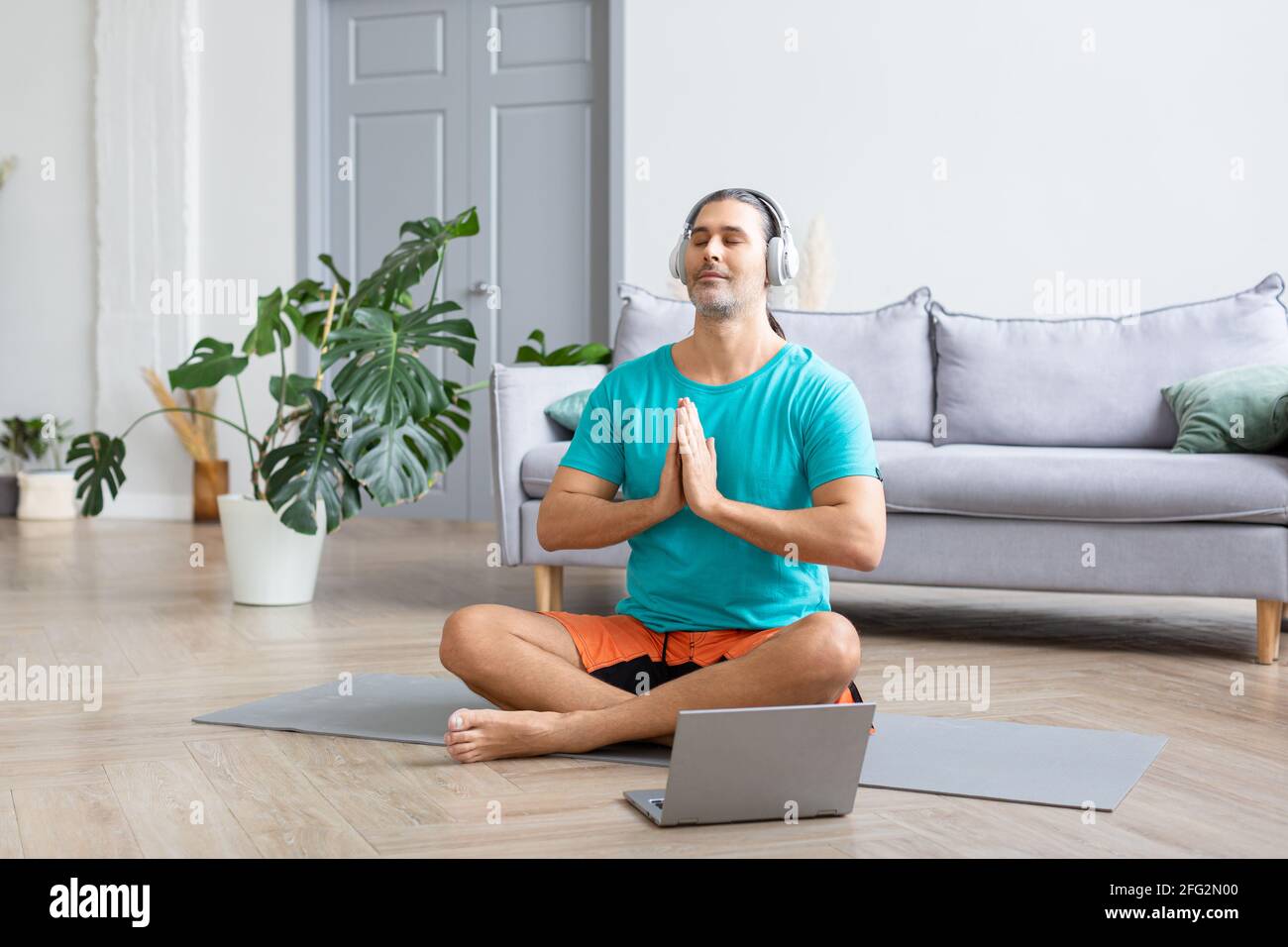 Photo of a man meditating at home - using from the internet to monitor ...
