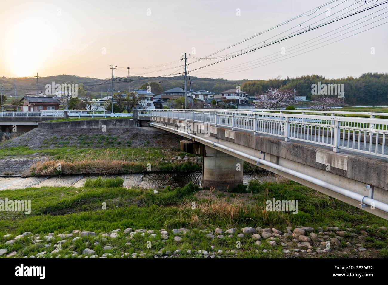 Empty bridge over quiet stream in rural japanese neighborhood at sunset ...