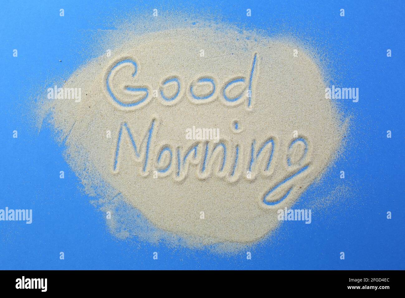 The word good morning is written in the sand on a blue background Stock ...
