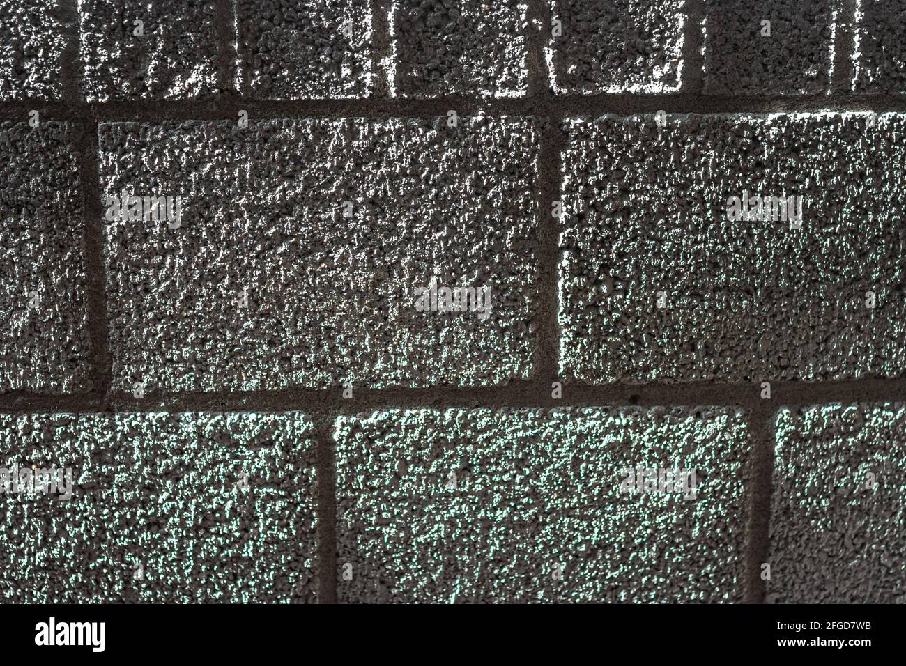 Sunlight shines just past a brick wall, creating a textured effect ...