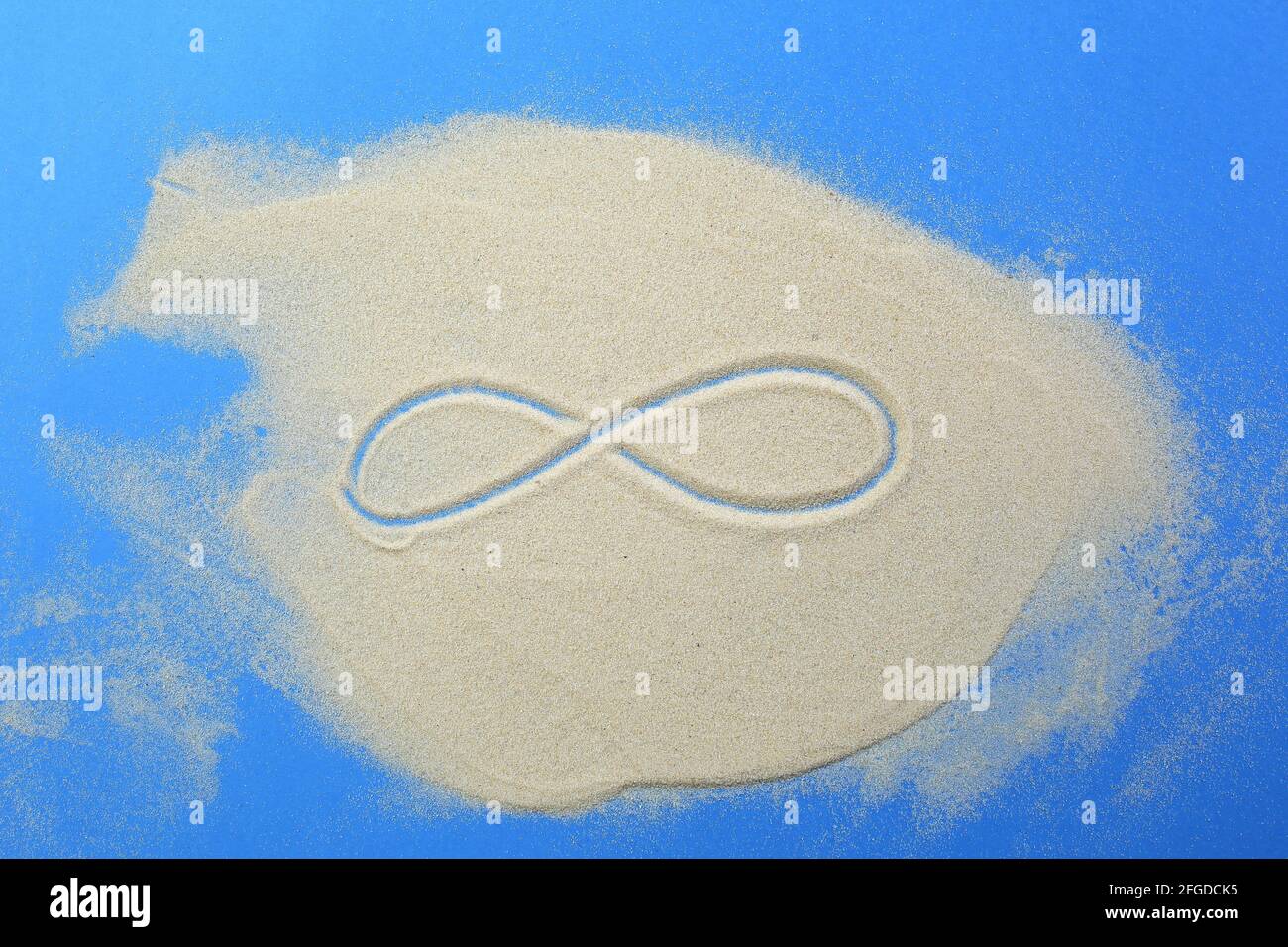 Infinity symbol written in sand on a blue background Stock Photo - Alamy
