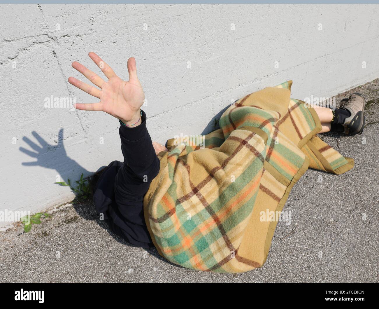 poor young beggar while he tries to rest on a bed on the sidewalk of ...