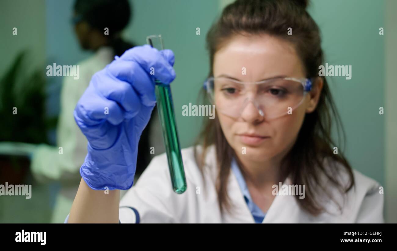 Chemist researcher woman holding test tube with dna liquid observing ...