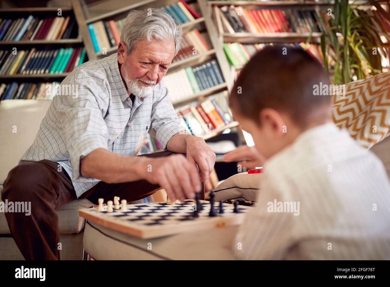Grandpa and his little grandson playing the chess in a family ...