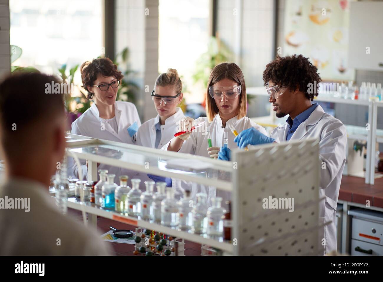 Young students mix chemicals in a test tube in a sterile laboratory ...