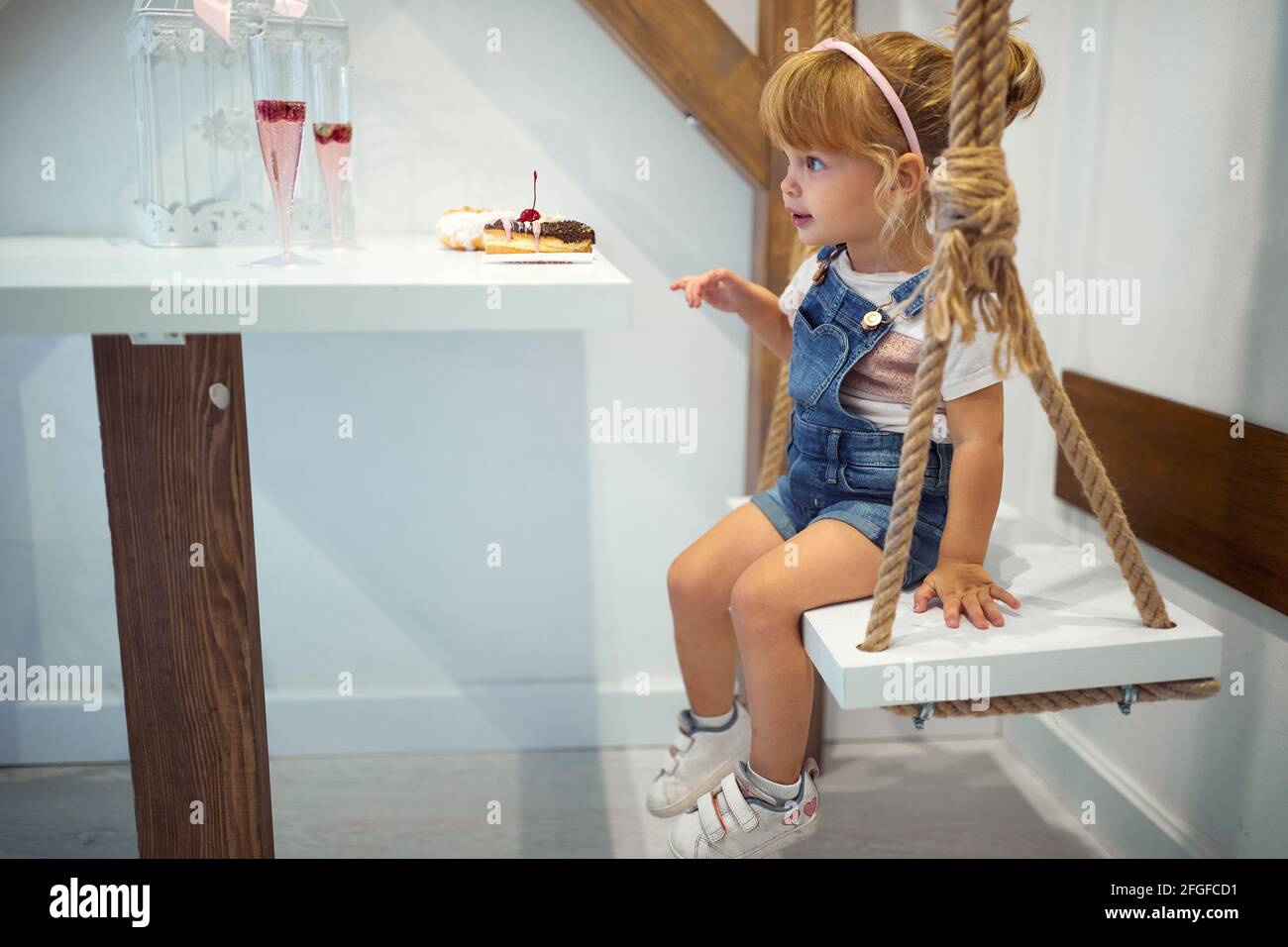 A little girl is sitting in a pastry shop and enjoying delicious donuts ...