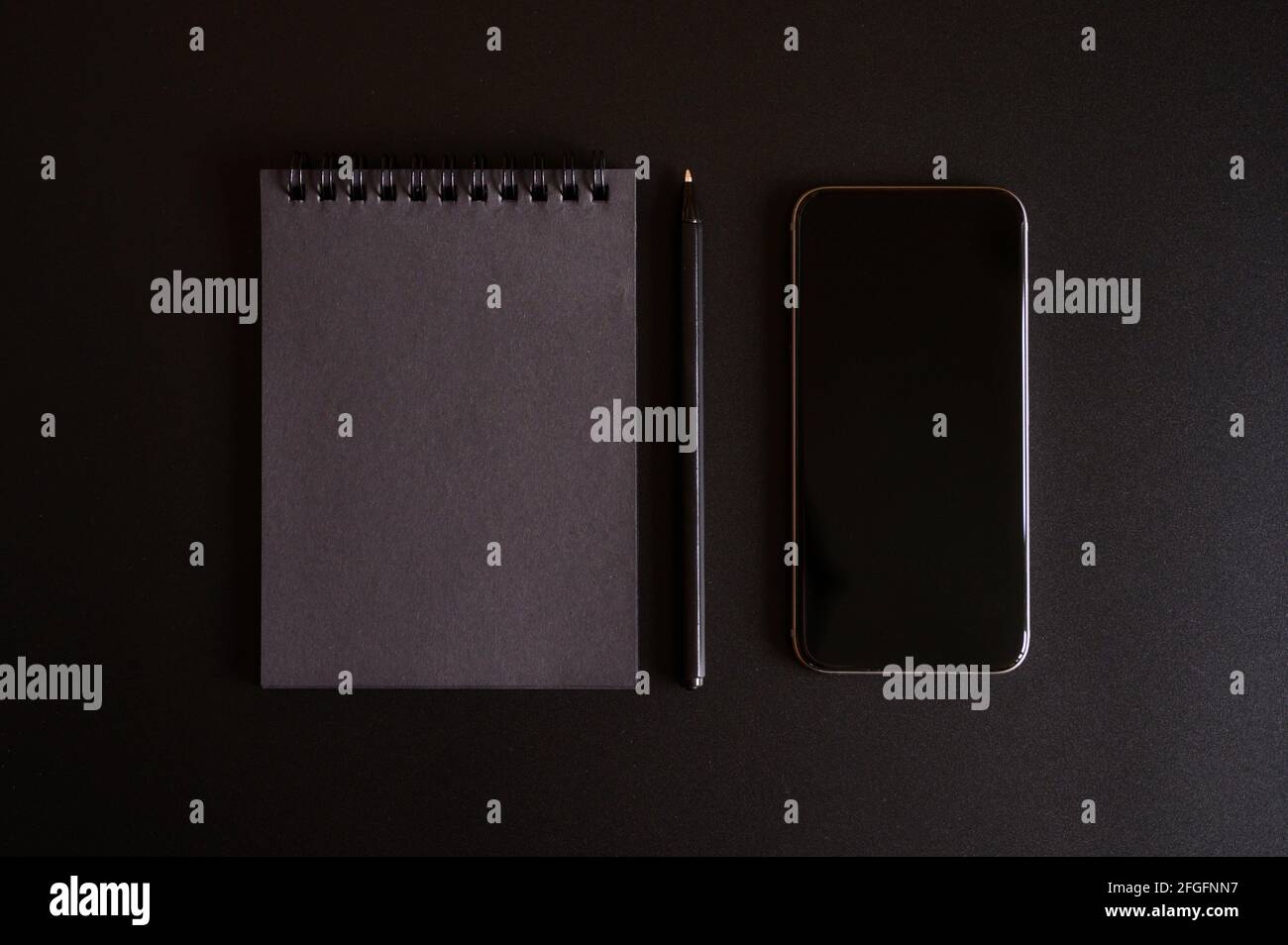 notebook on a spring with black sheets, and a pen, and mobile phone on ...