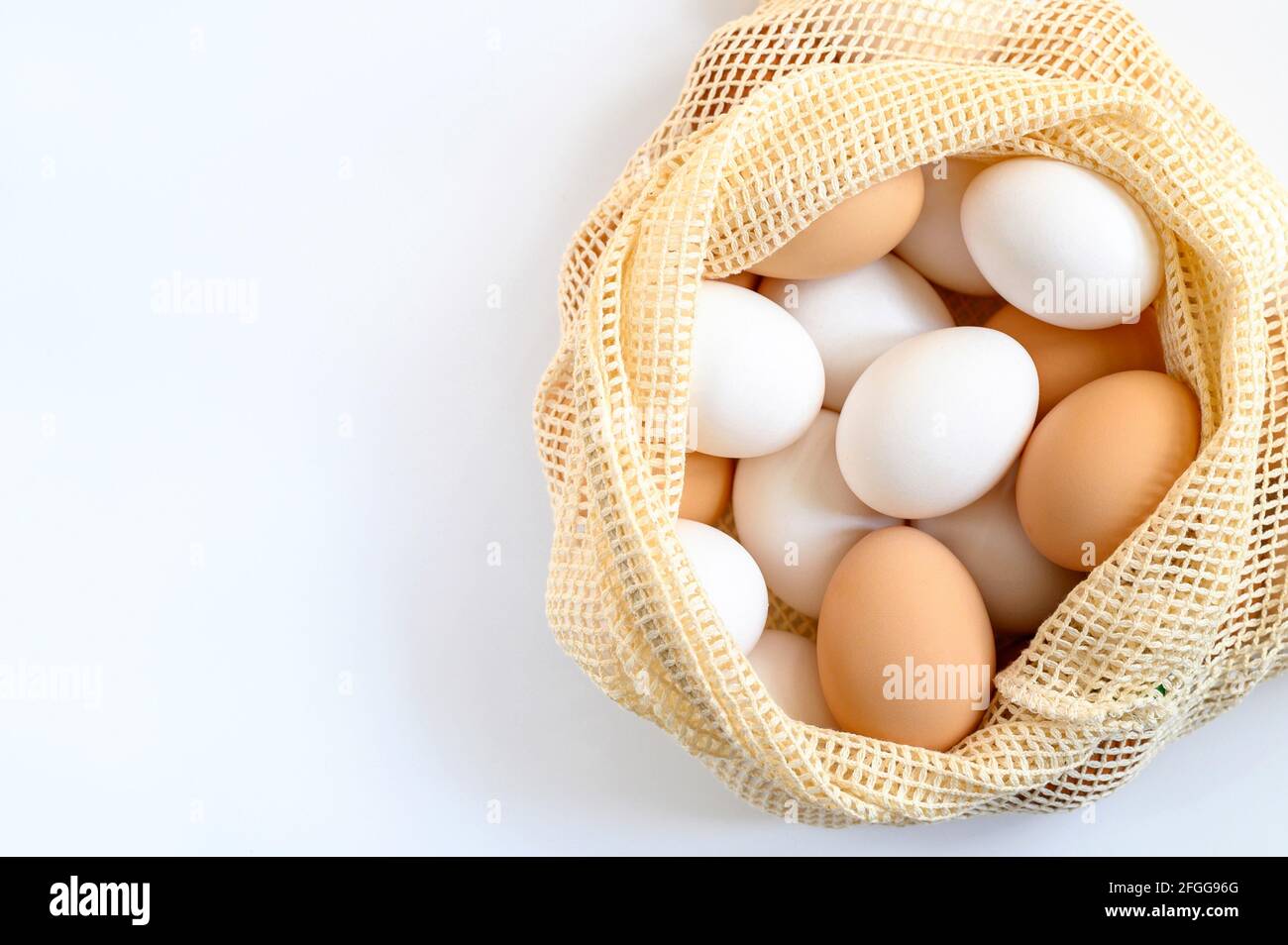 chicken eggs white and brown color in a beige reusable mesh bag on a ...