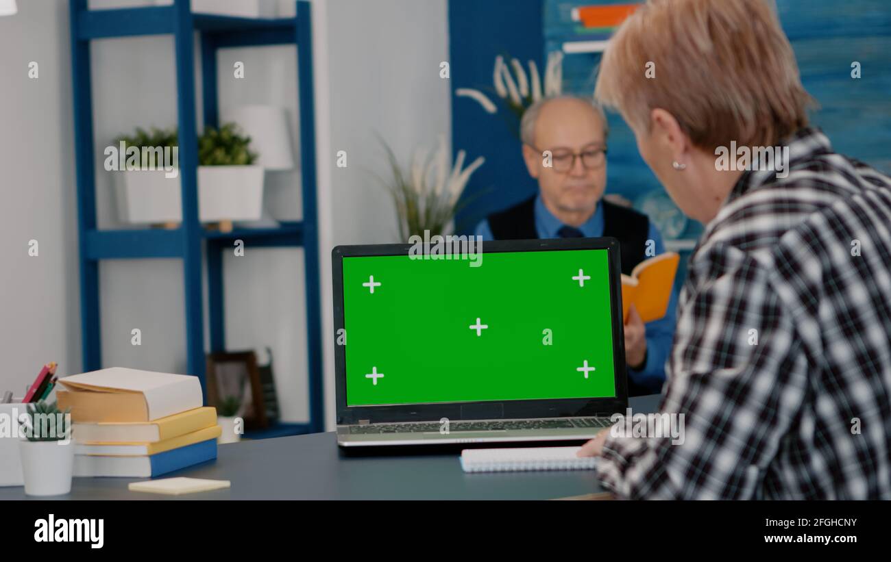 Elderly person reading on green screen, mock up, chroma key display of ...