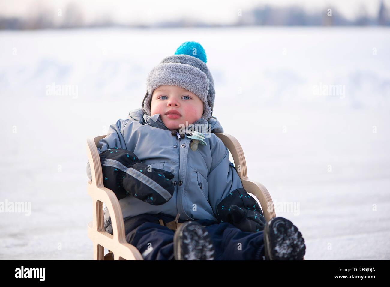 Little baby boy sitting in a sleigh. Cute little boy sitting on her ...