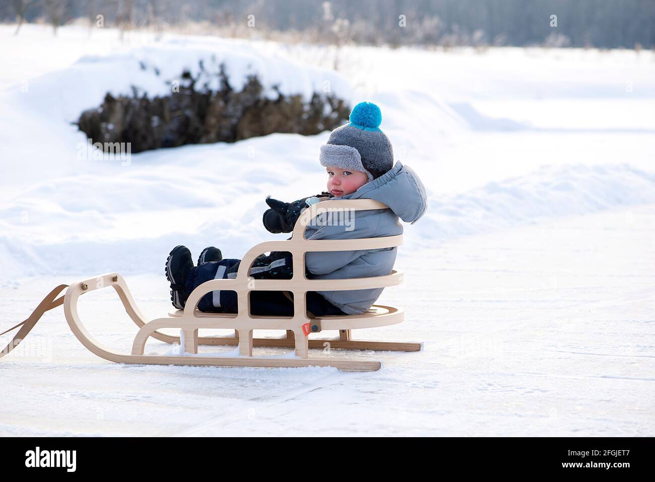 Little boy sitting in a sleigh. Cute little boy sitting on her sledge ...