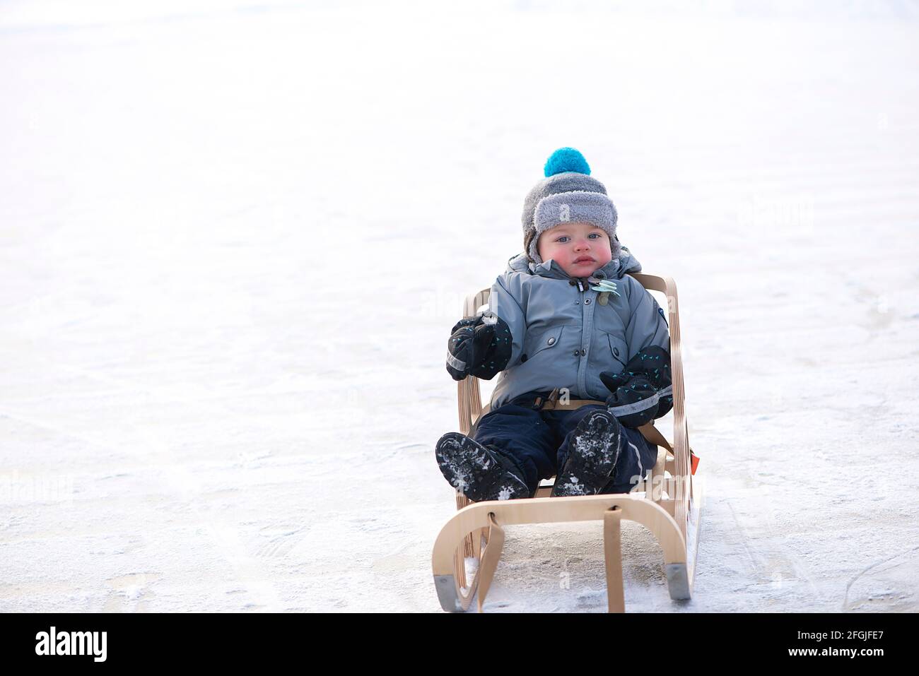 Little boy sitting in a sleigh. Cute little boy sitting on her sledge ...