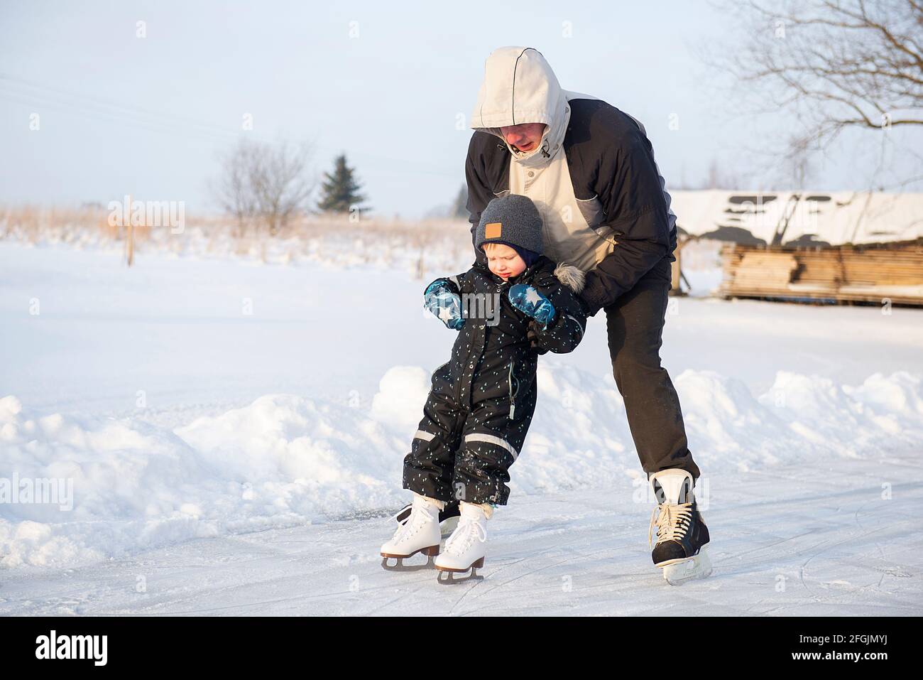 Grandfather teaching her little grandson ice skating at outdoor skating ...