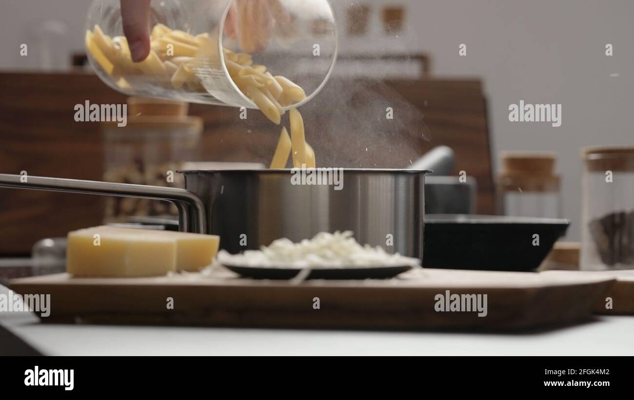 man pouring dry penne into saucepa with boiling water, wide photo Stock ...