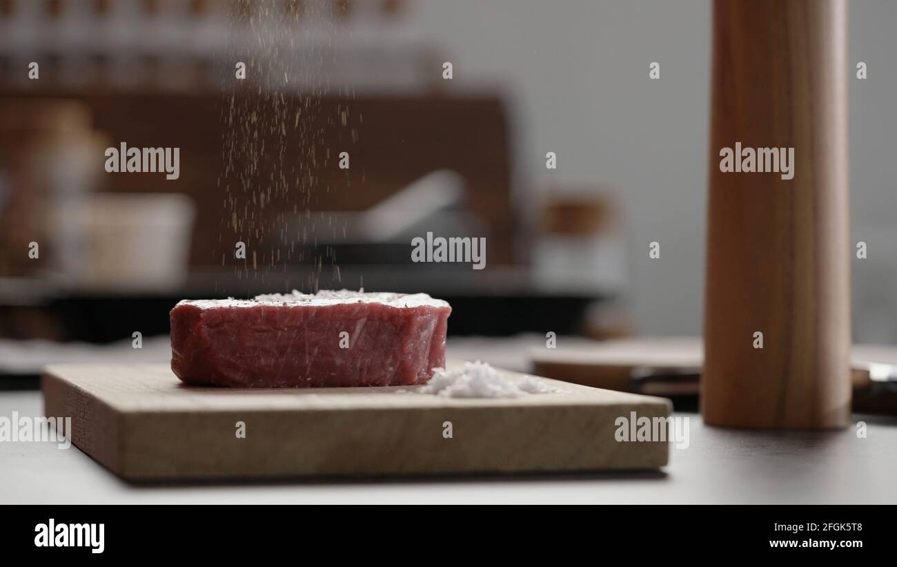 man seasoning raw beef steak resting on oak board closeup, wide photo ...