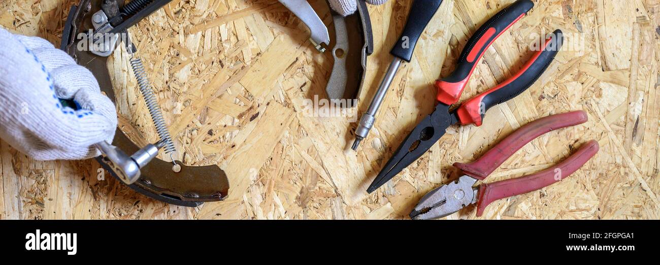 car drum brake disassembled in men's gloved hands and a set of various ...