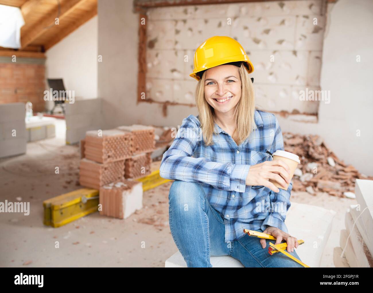 pretty young worker woman with yellow safety helmet takes coffee break ...