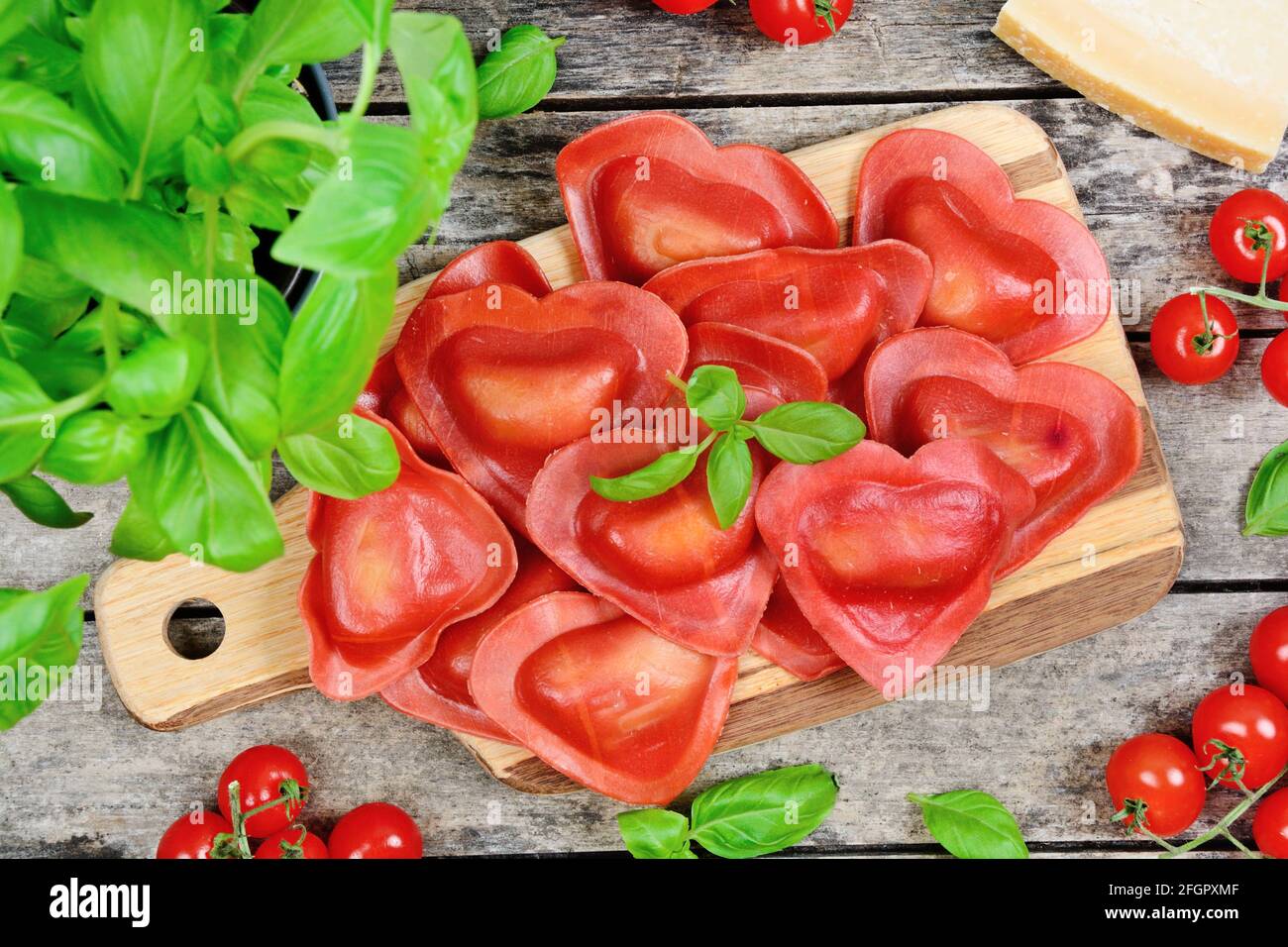 Red heart ravioli with tomato, mozzarella and basil on a wood ...