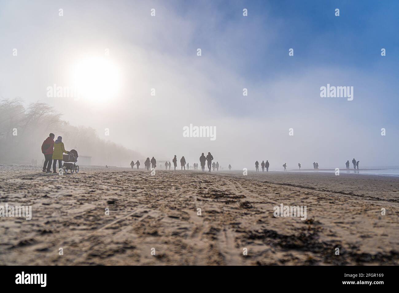 Crowd of people walking on a beach on foggy spring day Stock Photo - Alamy