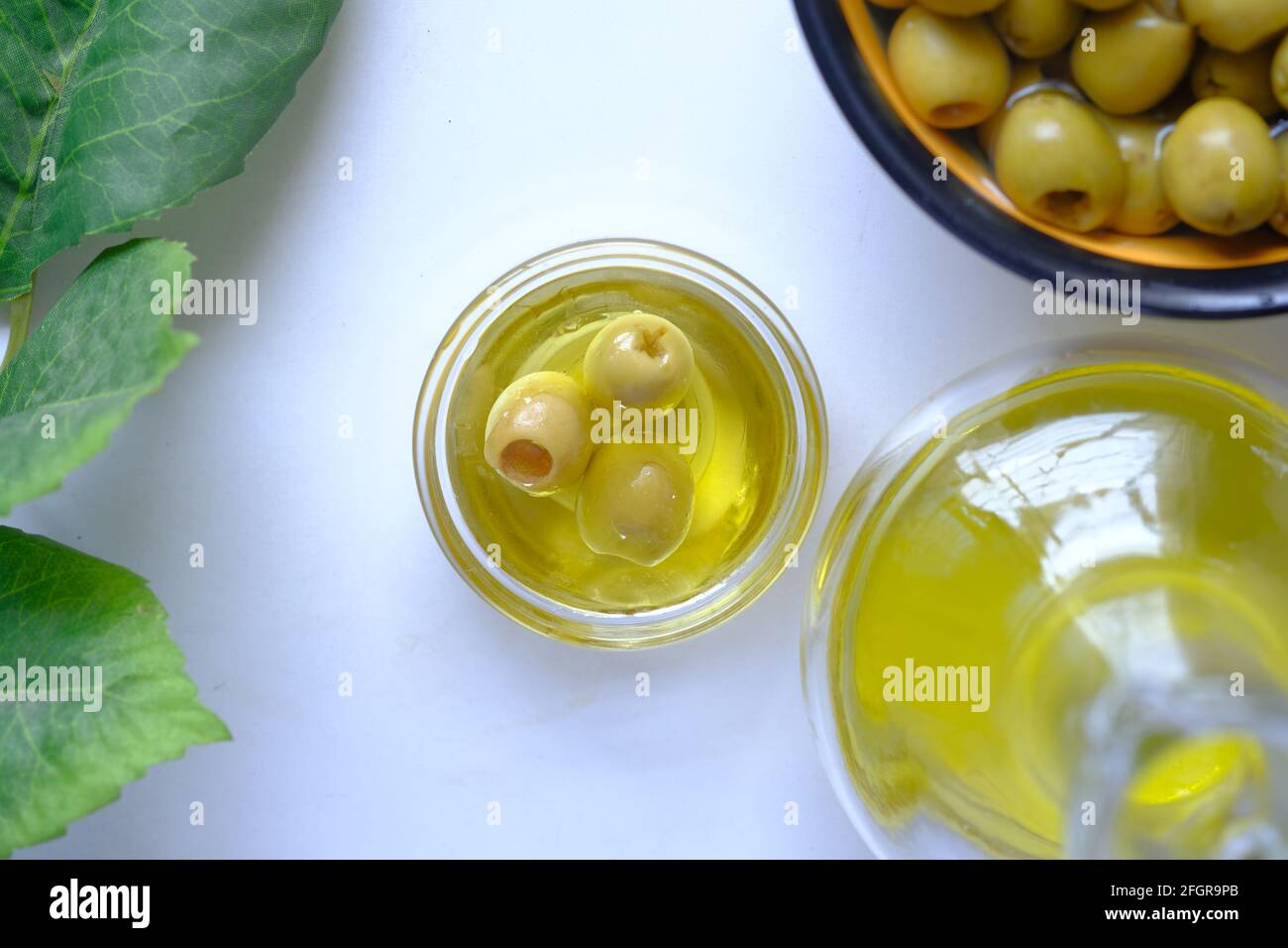 bottle of olive oil and fresh olive in a container on white background ...