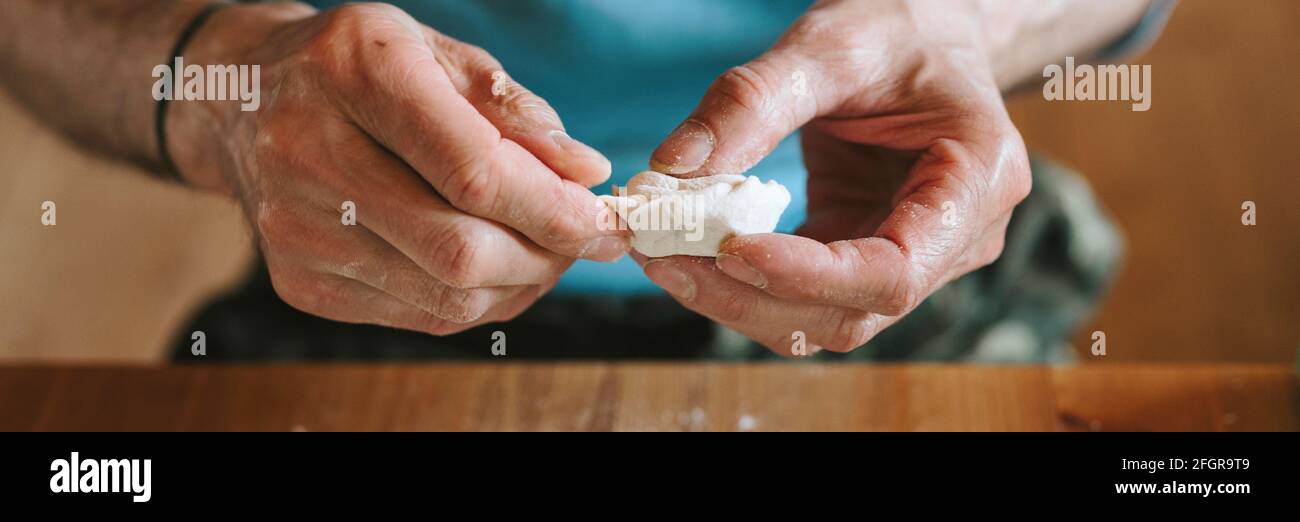 hands of senior man cooking and molding small homemade uncooked ...