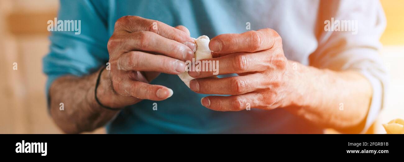 hands of senior man cooking and molding small homemade uncooked ...