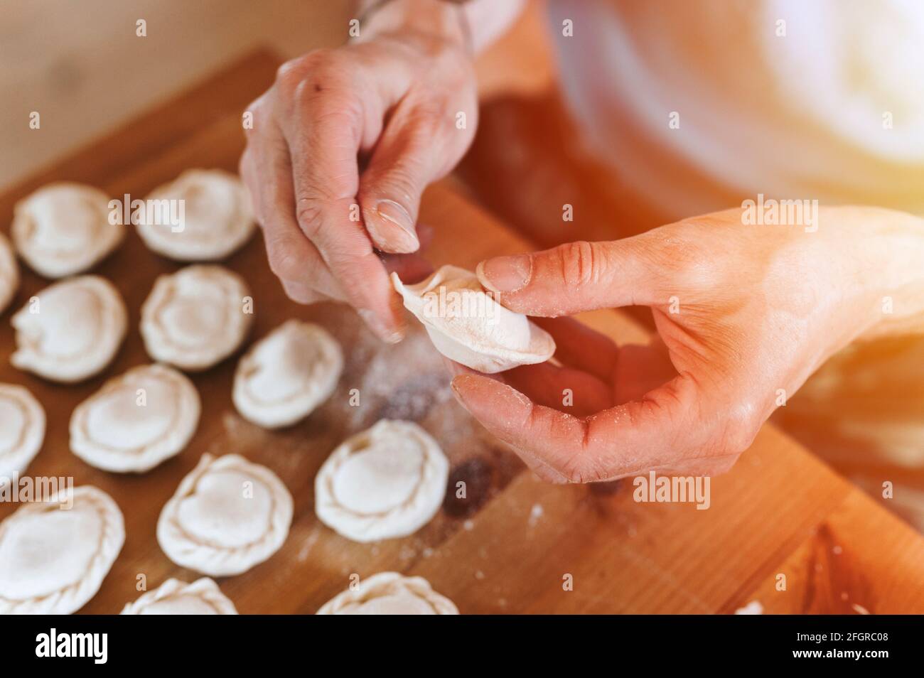 hands of senior man cooking and molding small homemade uncooked ...
