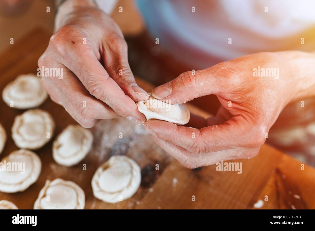 hands of senior man cooking and molding small homemade uncooked ...