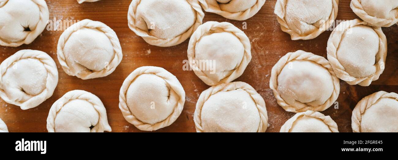 pile of small homemade uncooked dumplings with meat on kitchen table ...