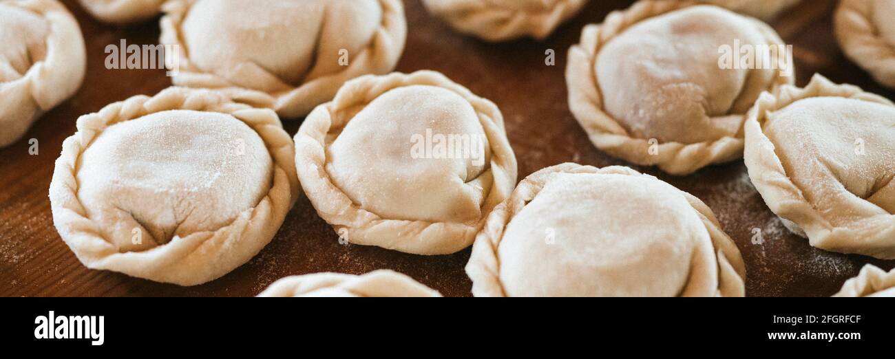 pile of small homemade uncooked dumplings with meat on kitchen table ...