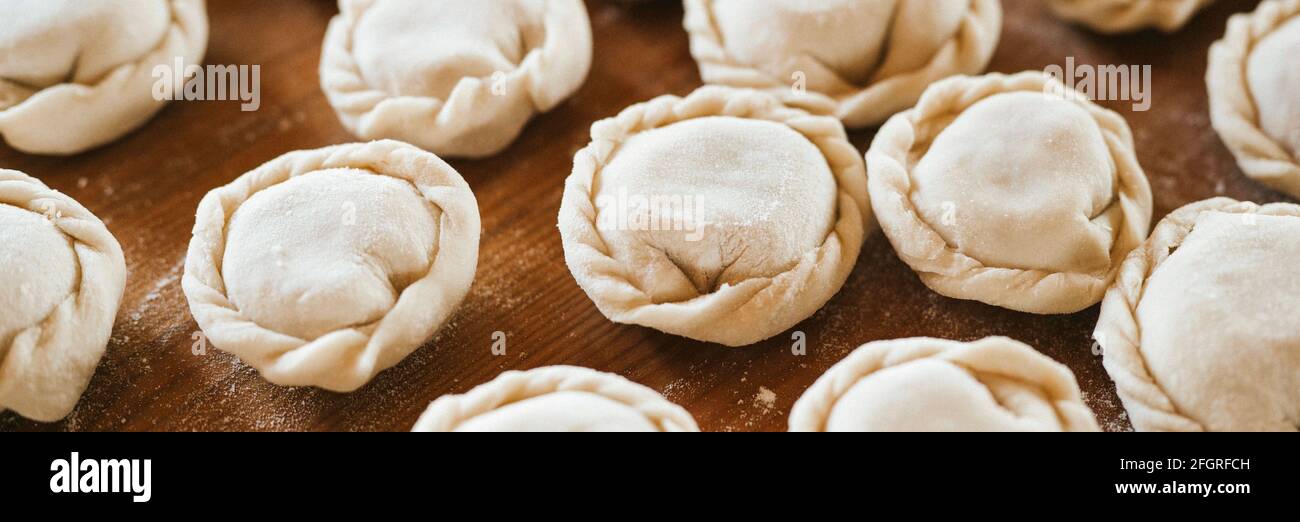 pile of small homemade uncooked dumplings with meat on kitchen table ...