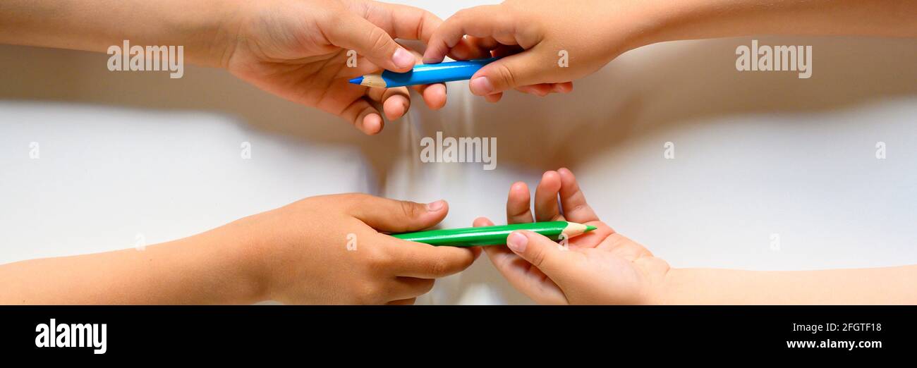 kid's hands share each other colored pencils on a white background ...