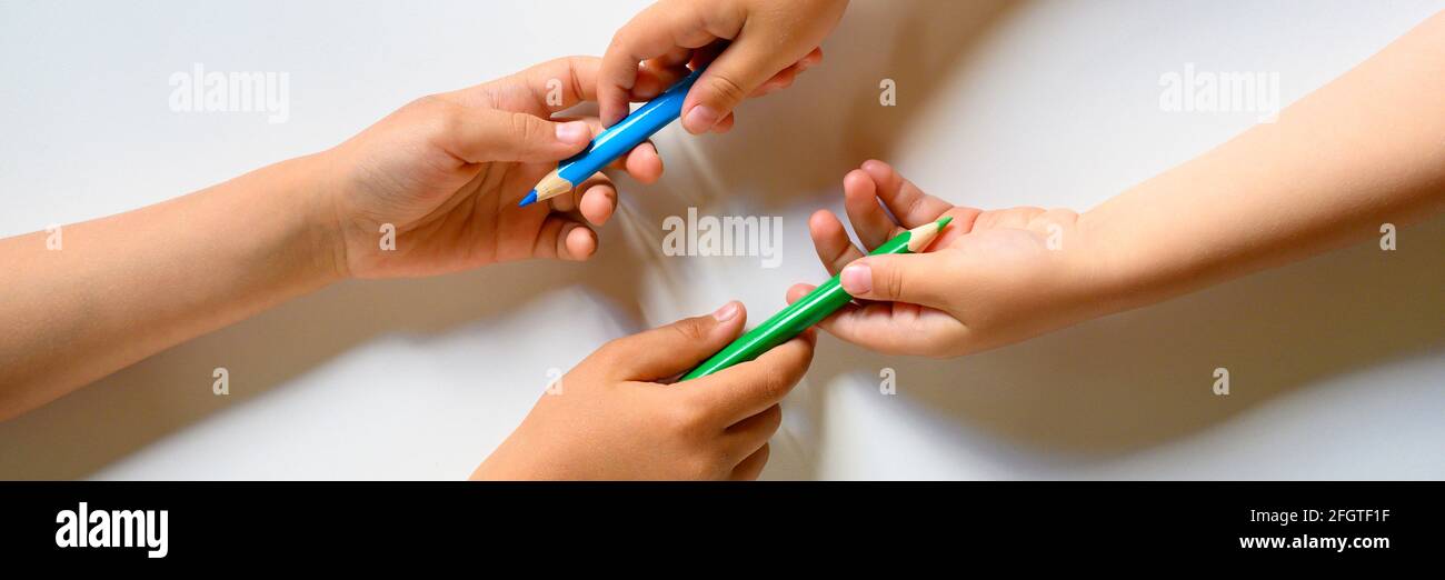 kid's hands share each other colored pencils on a white background ...
