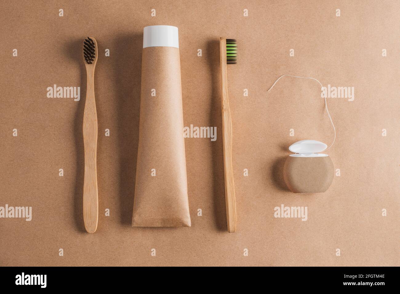 Wooden toothbrushes, organic toothpaste and dental floss on craft paper ...