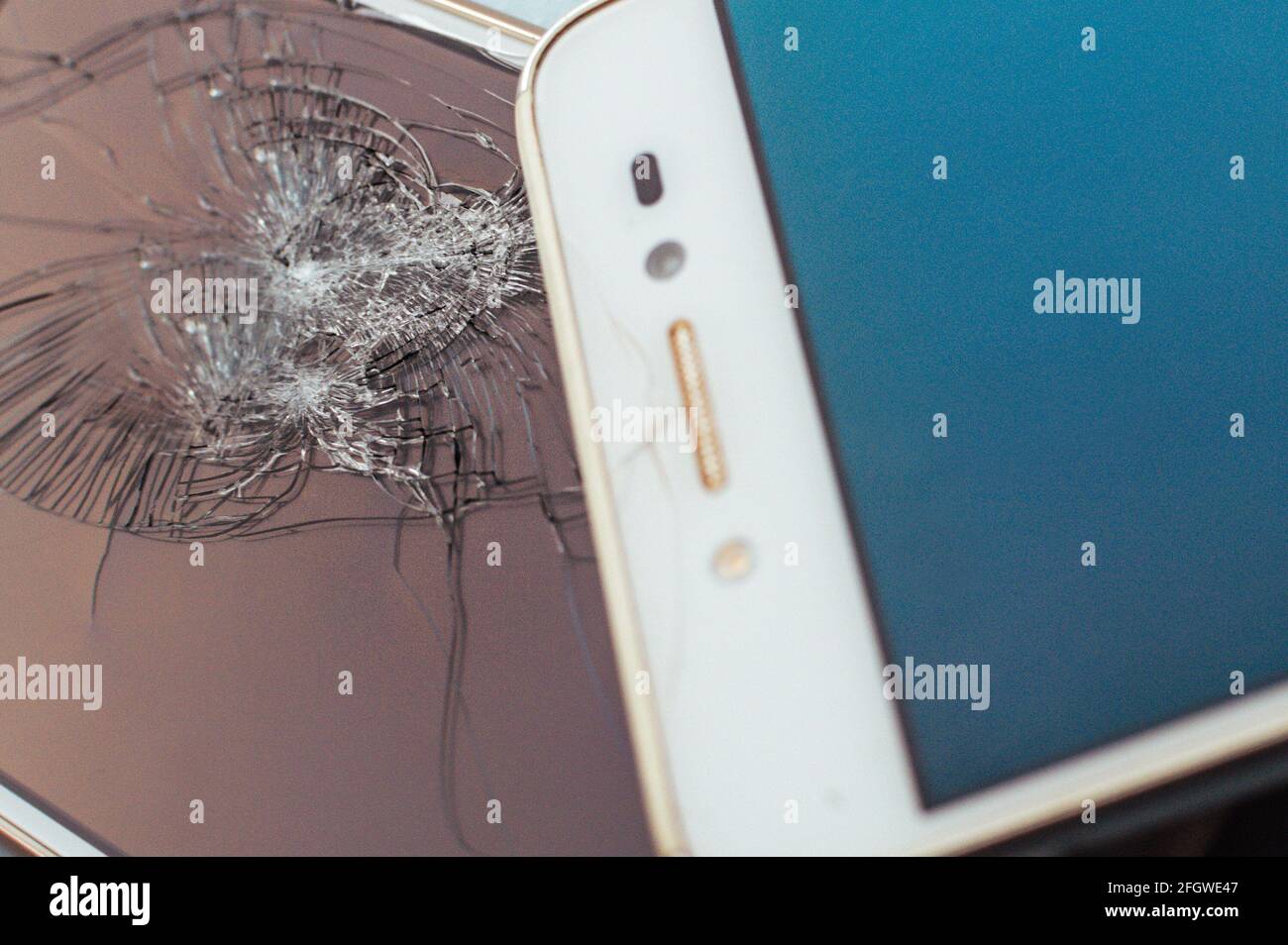 Two mobile phones close-up with broken screens Stock Photo - Alamy