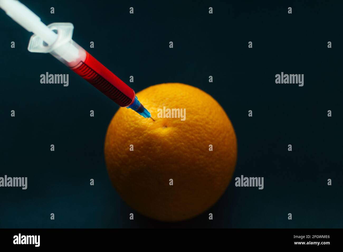 Syringe and orange on a black background. Concept Genetic Engineering ...