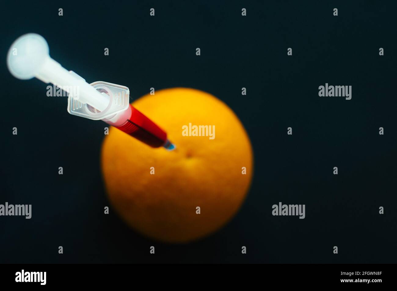 Syringe and orange on a black background close-up. Concept Genetic ...