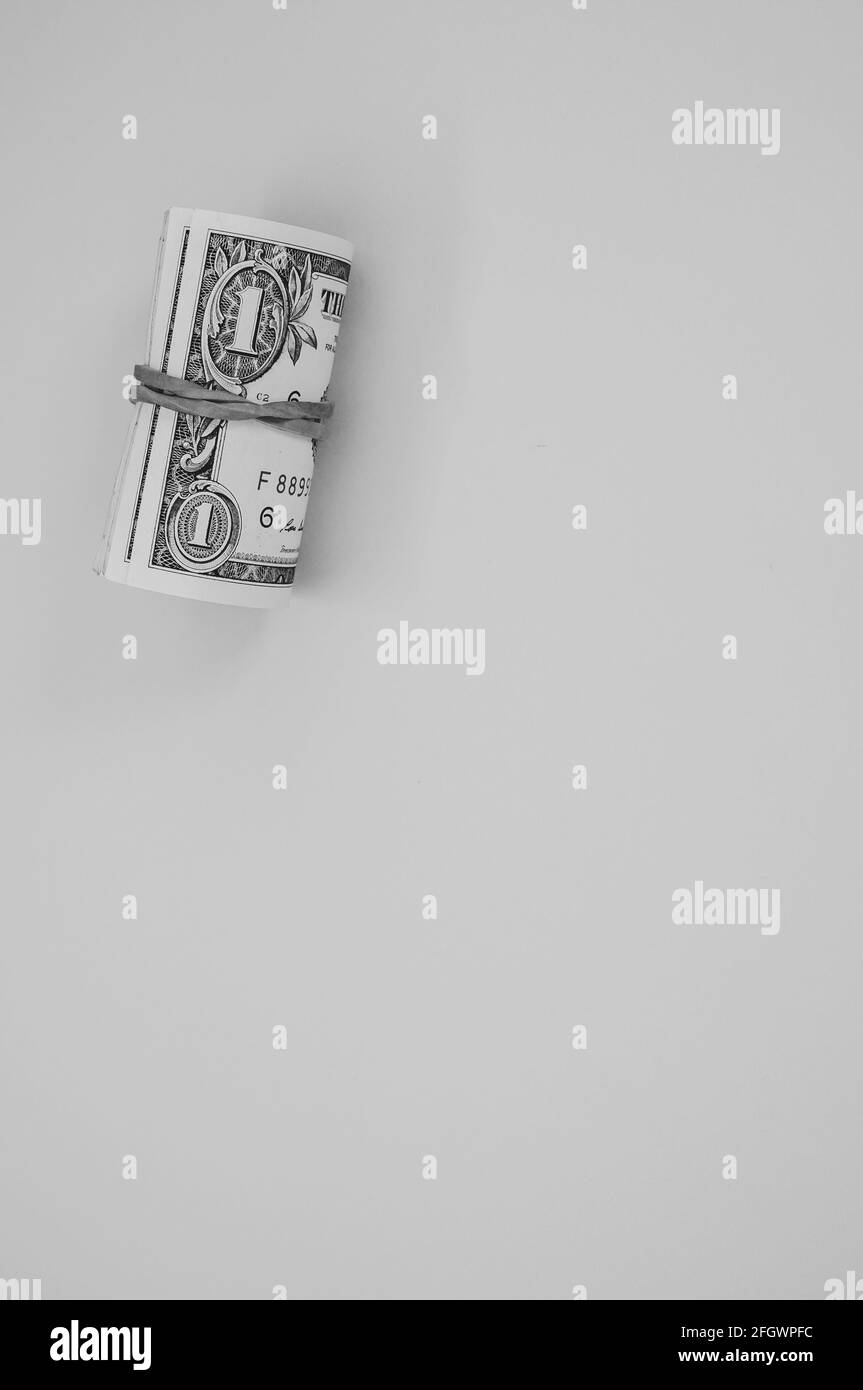 A grayscale of a roll of dollars on an empty background for a copy ...